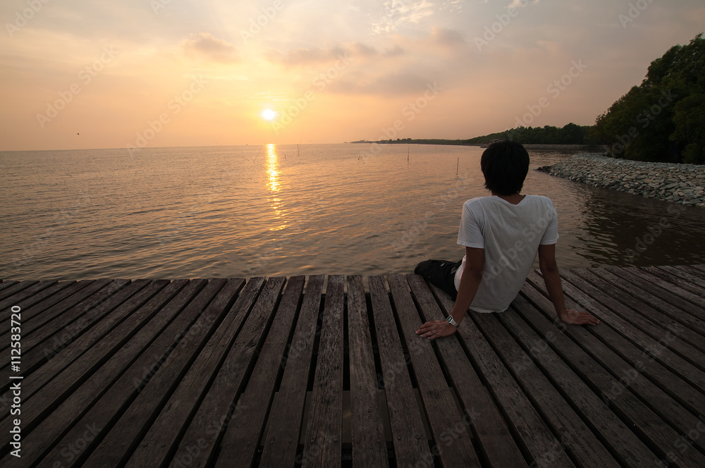silhouette Young man relax siting on pier sea beach looks to right with ...