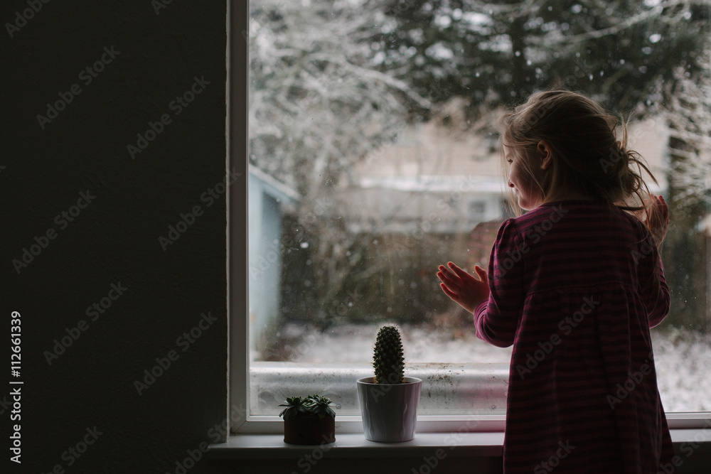 Little girl looking through window Stock Photo | Adobe Stock