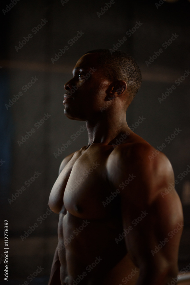 African american bodybuilder model showing muscles in studio on black ...