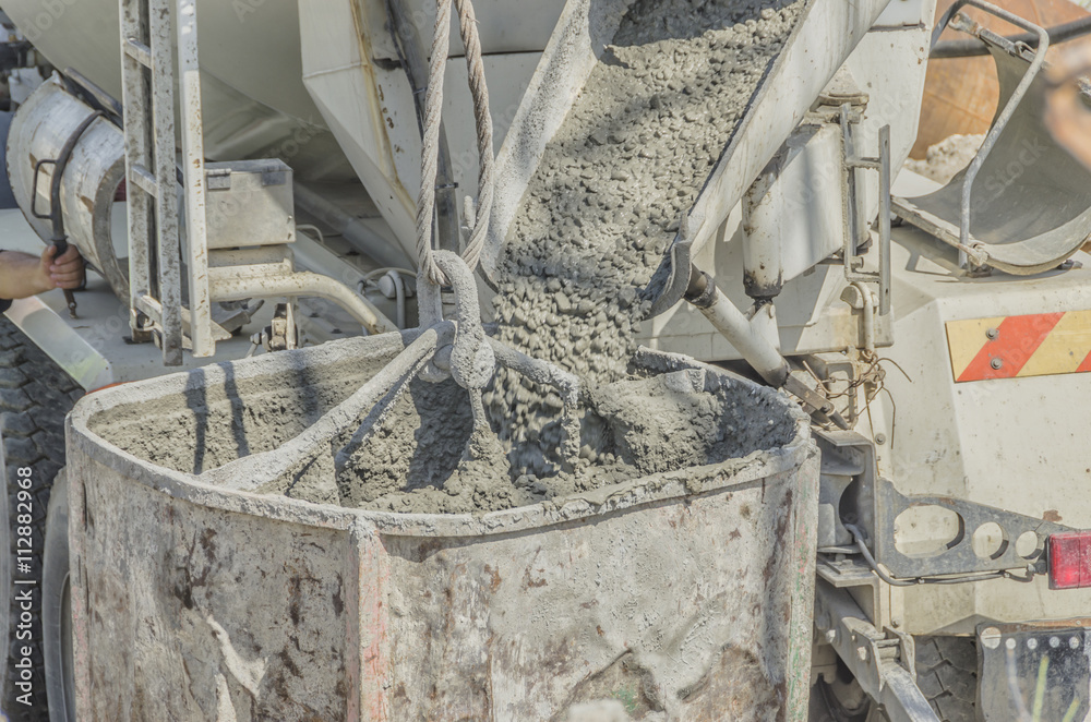 Concrete mixer truck pouring liquid concrete into the tower crane ...
