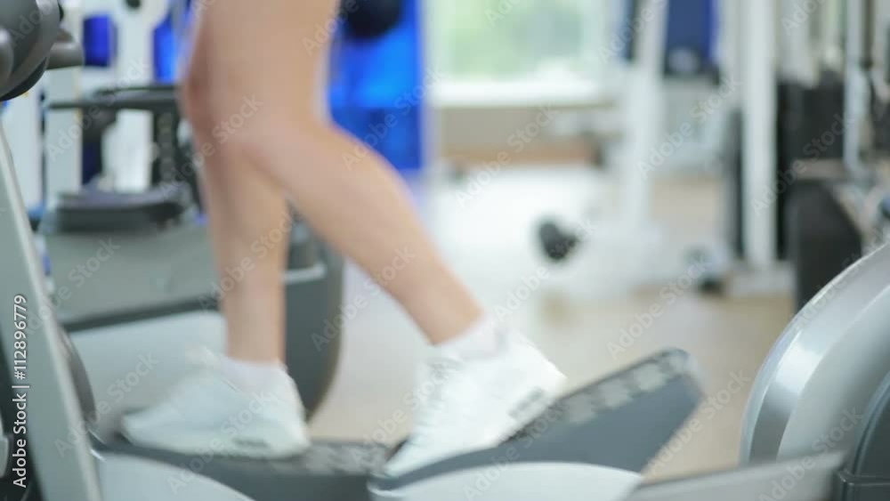 Girl In Gym On Simulator The Woman With Athletic Legs Walking On The Steppers Vídeo Do Stock