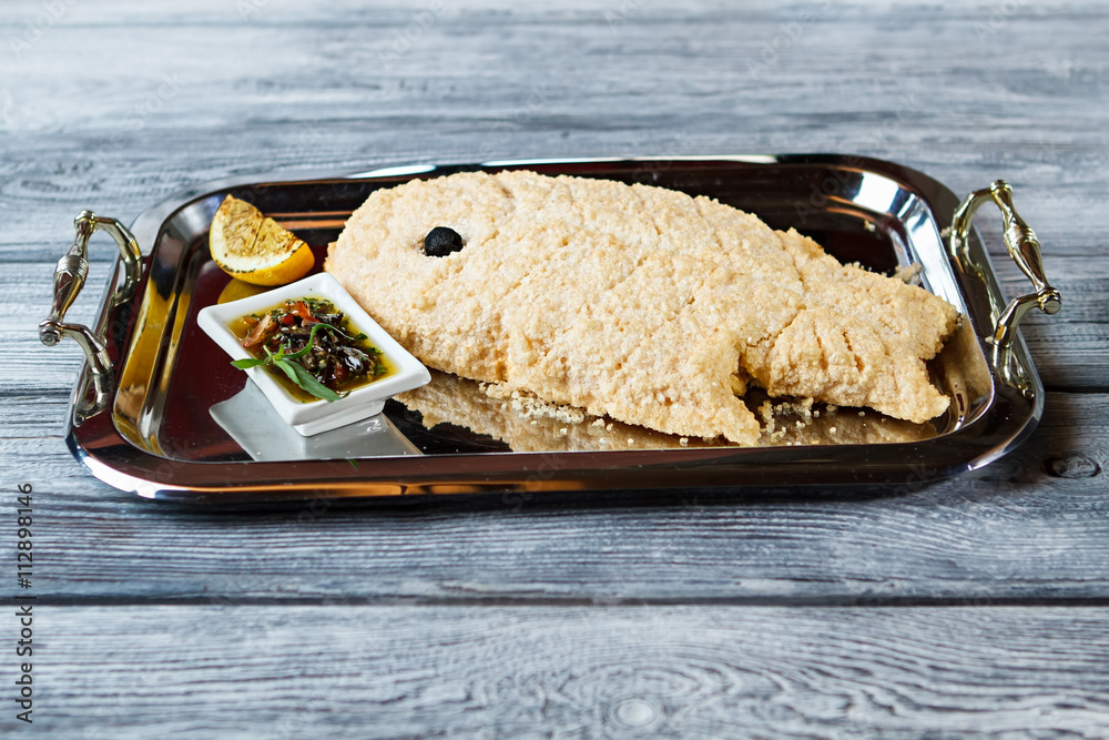 Breaded fish on tray. Fish with lemon and herbs. Dorado fish in sea ...