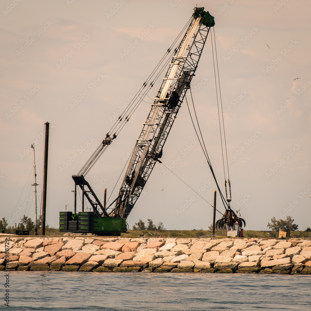 Grab crane in action for building a seawall. Stock Photo | Adobe Stock