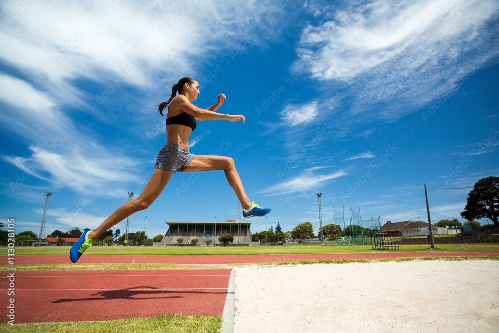 Female athlete performing a long jump Stock Photo | Adobe Stock