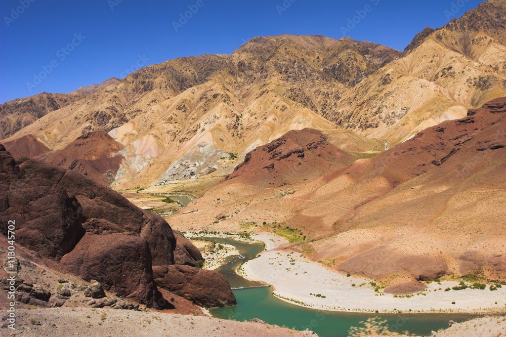 Hari Rud river flows through fertile valley at base of red rock ...