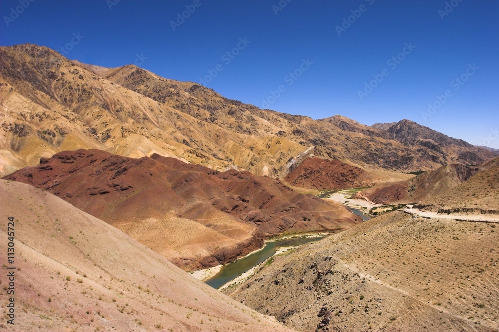 Hari Rud river flows through fertile valley at base of red rock ...