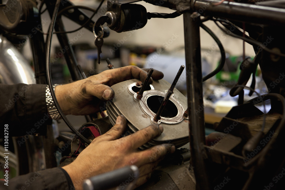 Mechanic attaching cylinder to motorcycle Stock Photo | Adobe Stock