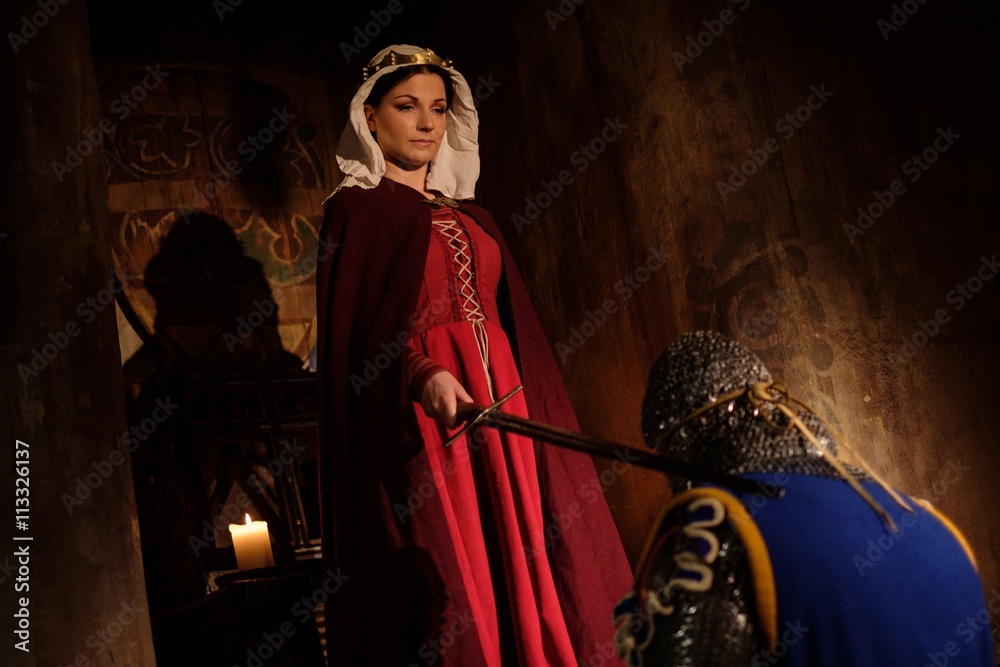 Medieval queen doing knighting ceremony in ancient castle interior ...