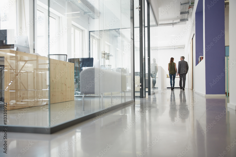 Businessman and woman walking down office corridor Stock Photo | Adobe ...