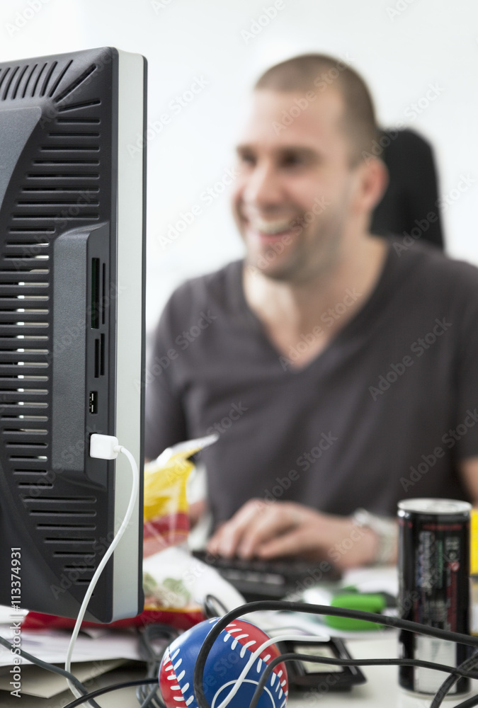 Smiling man sitting by computer Stock Photo | Adobe Stock