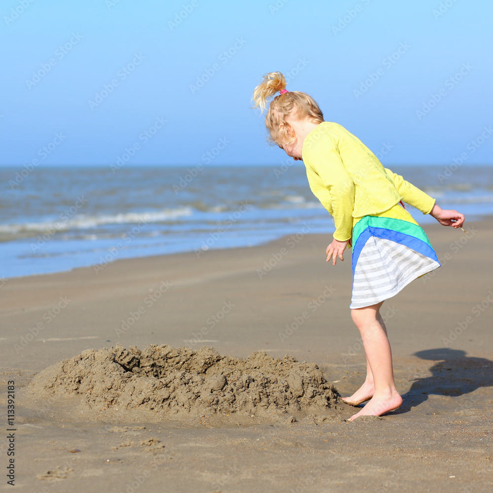 Cute active child wearing colorful dress playing on wide sandy beach ...