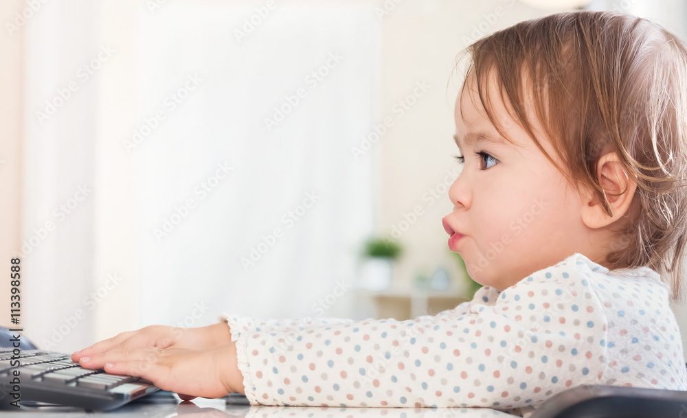 Little girl typing on her computer keyboard Stock Photo | Adobe Stock