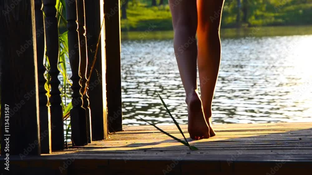 girl walks on a wooden pier on toes. girl stepping on toes gently on ...