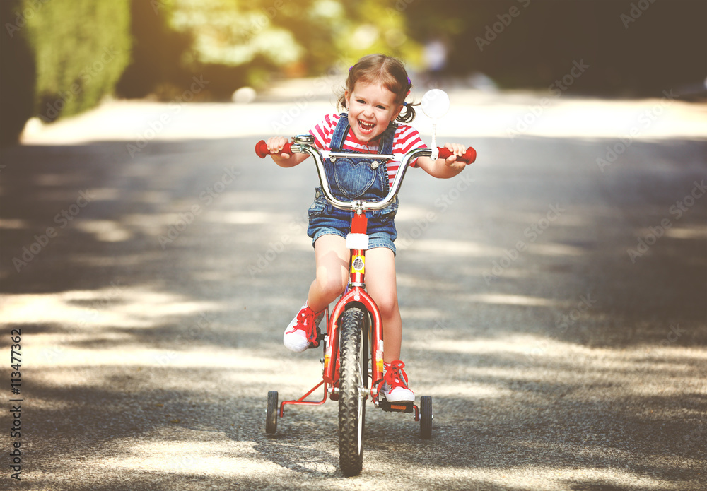 happy child girl cyclist riding a bike Stock Photo | Adobe Stock