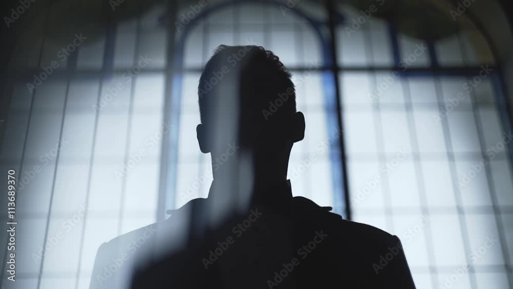 Close up shot of a silhouette of a man turns his head with windows on ...