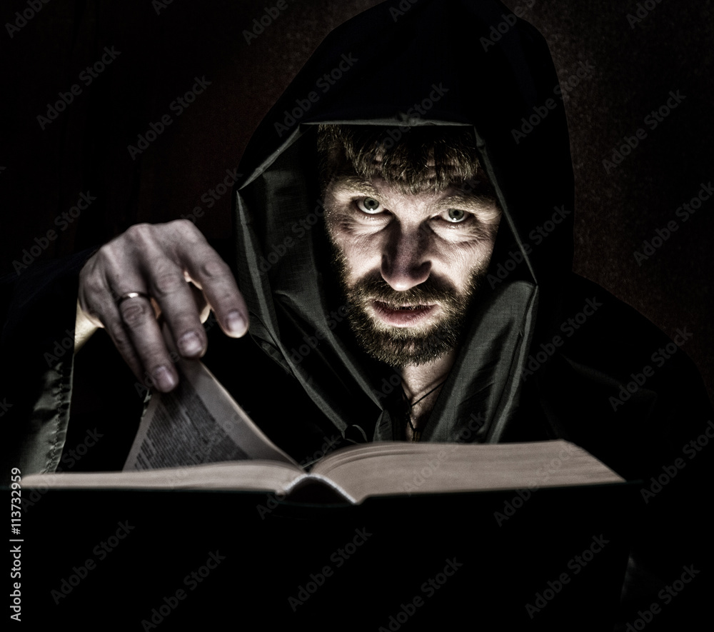 necromancer casts spells from thick ancient book by candlelight on a ...