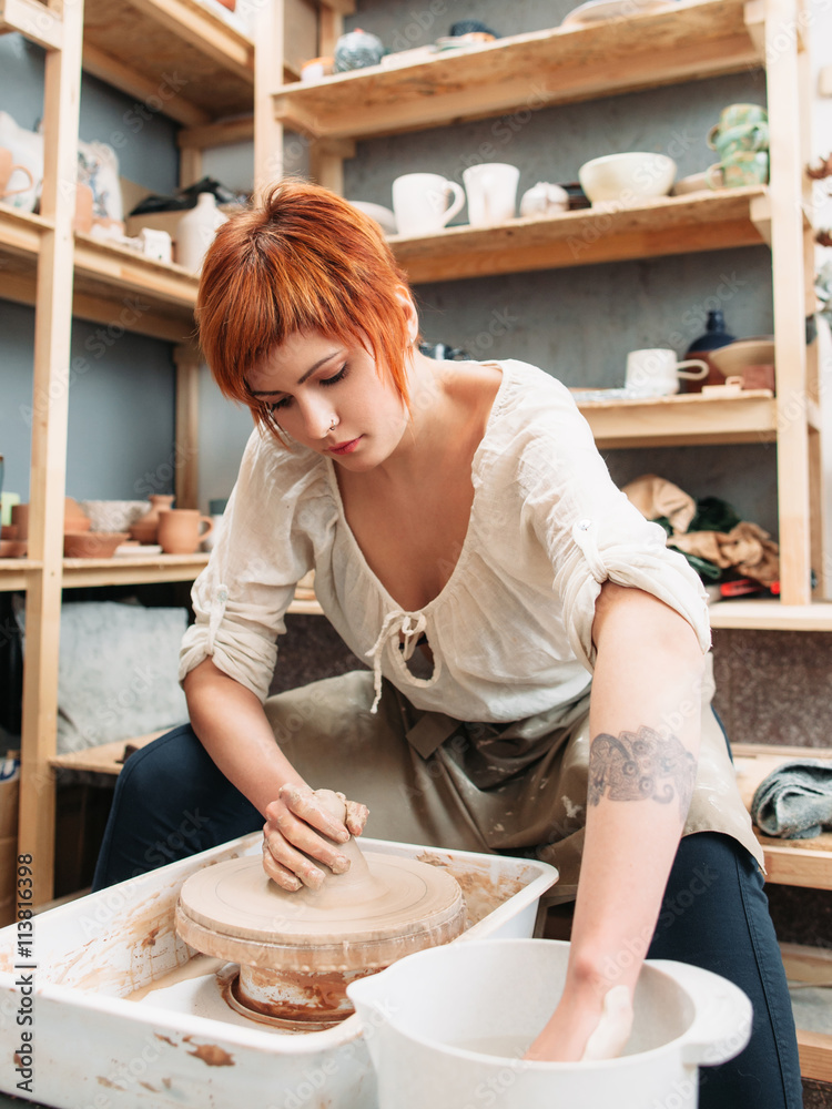 Young female potter working with clay at studio. Front view on red ...