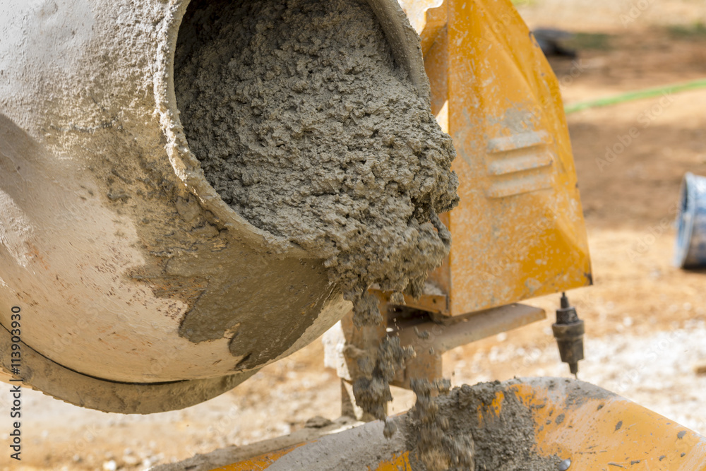 Pouring mortar from the cement mixer into a wheelbarrow. Building work ...