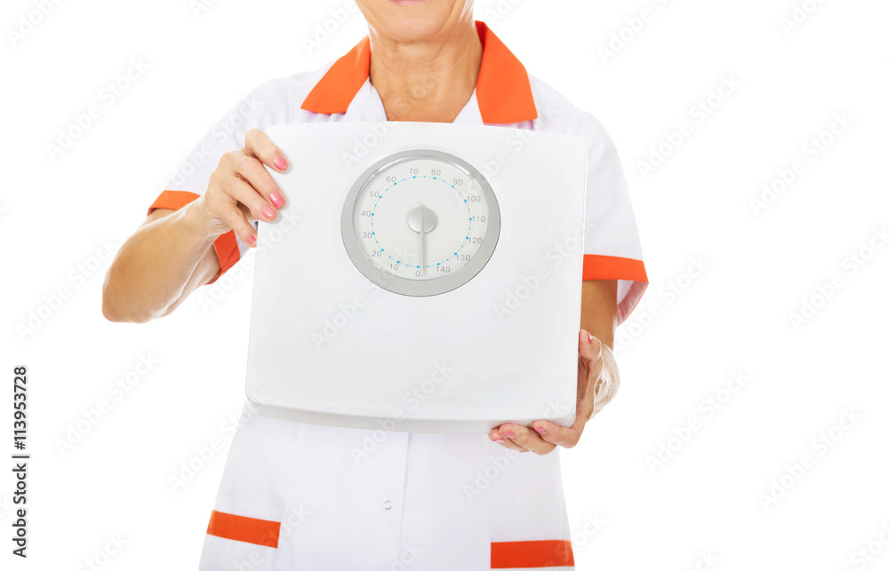 Elderly female doctor or nurse holds weigh scale Stock Photo | Adobe Stock