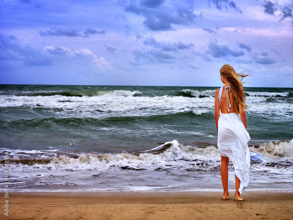 Summer girl sea. Girl goes next to wave on beach . Back view of girl on ...