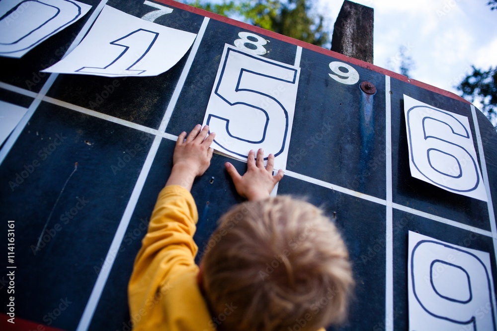 Young boy playing with numbers on scoreboard Stock Photo | Adobe Stock