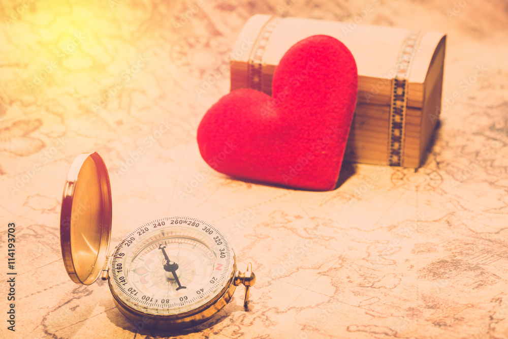 Vintage compassed on travel map and treasure chest and love heart ...