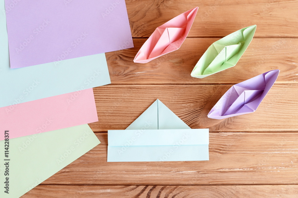 Set of colored ships on wooden background. How to fold paper ship ...