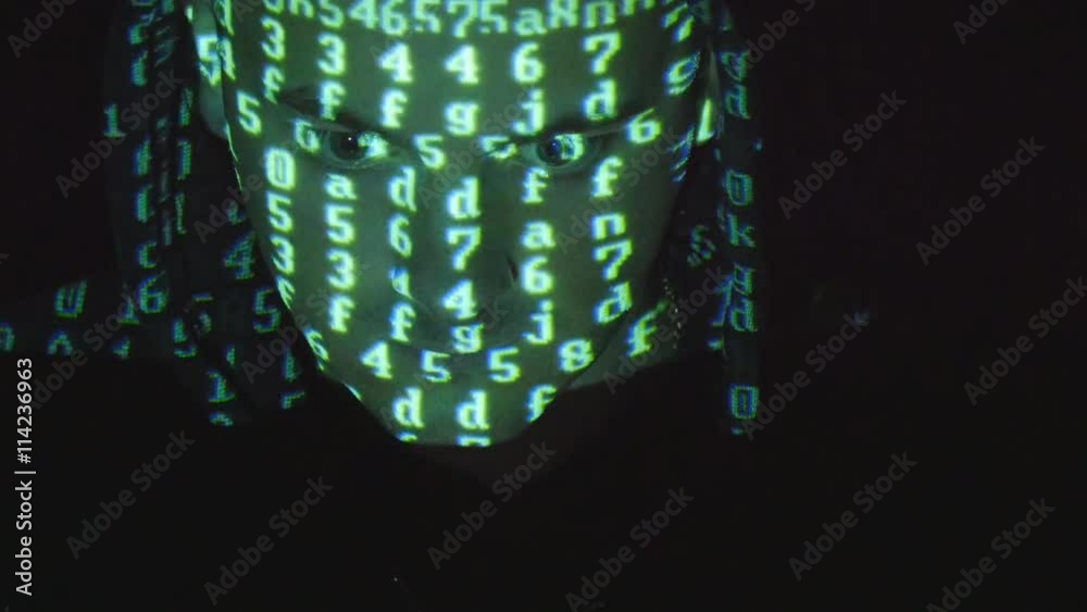 Close up shot of male face of hacker with binary code projections. Source code projected over an ...