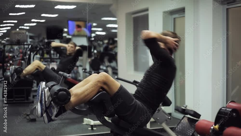 Man is engaged in lifting body on an inclined board with a twist. vídeo ...