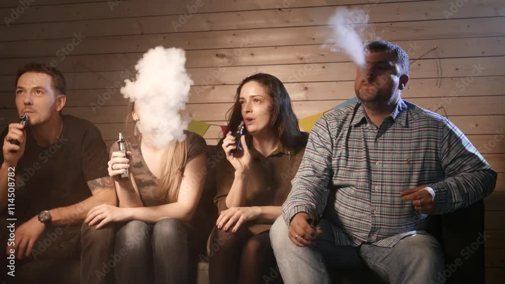 A group of people vaping, inhaling and exhaling large clouds of smoke ...