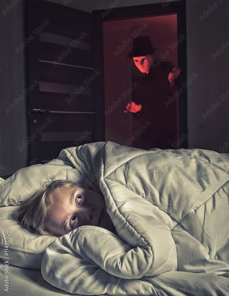 Nightmare. Scared boy lying in the bed while the masked stranger ...