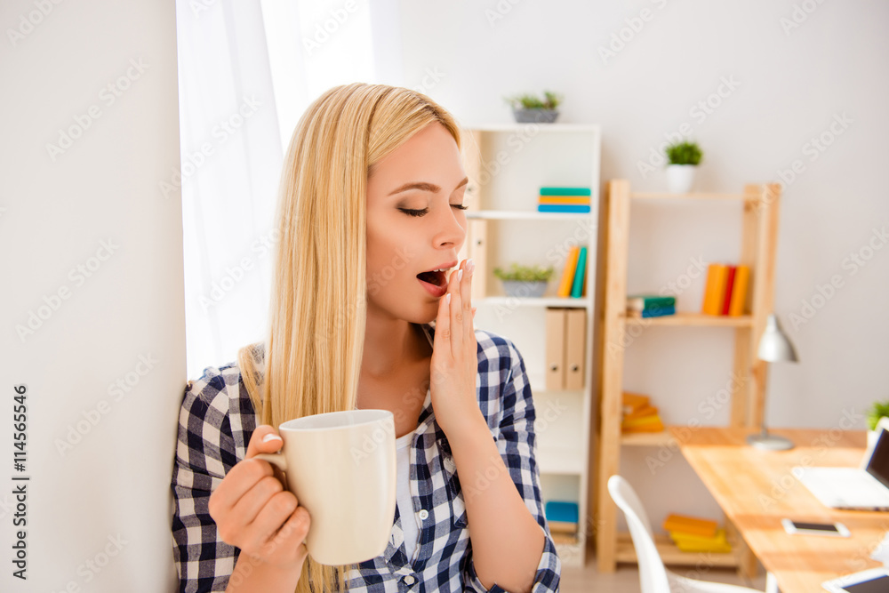Portrait of tired woman holding cup with coffee and yawning Stock Photo ...
