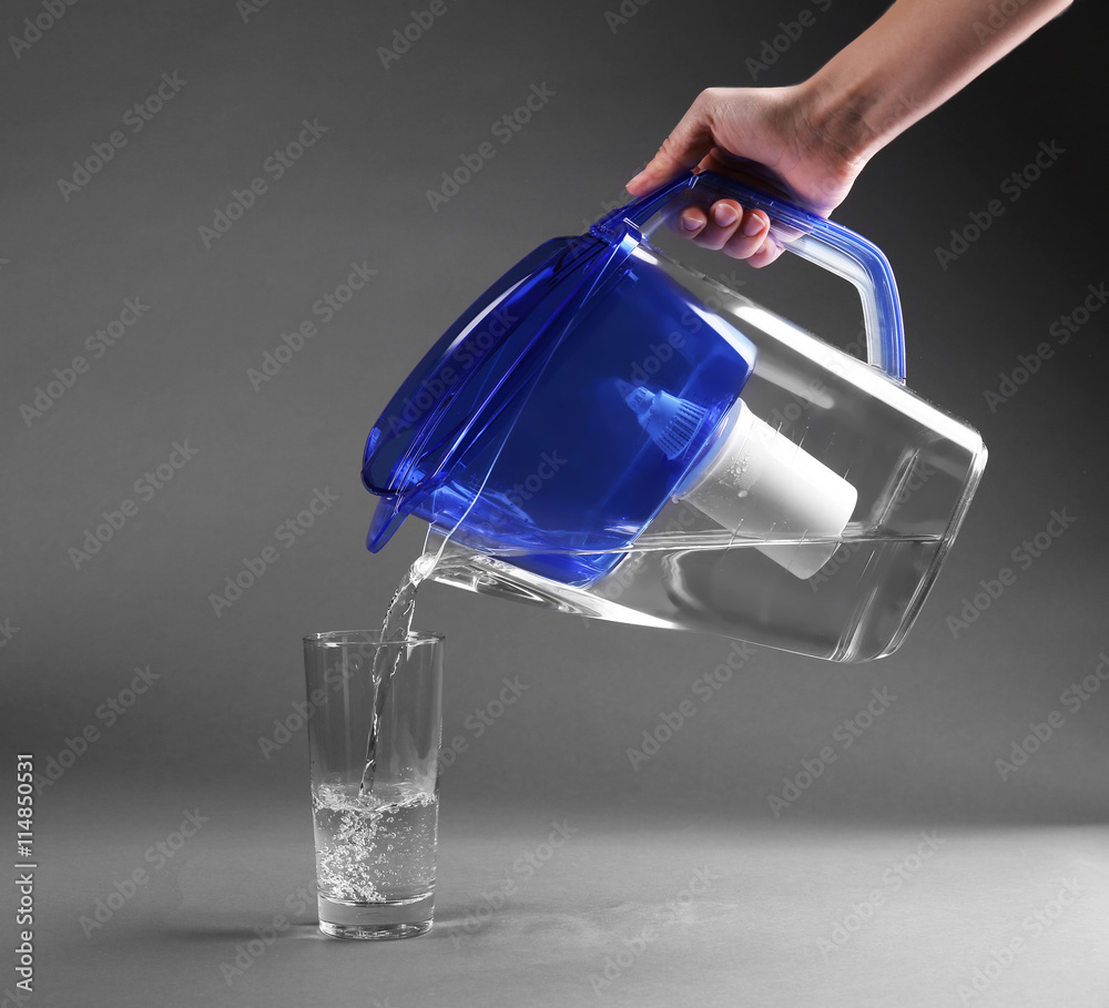 Female hand pouring water into glass on grey background Stock Photo ...