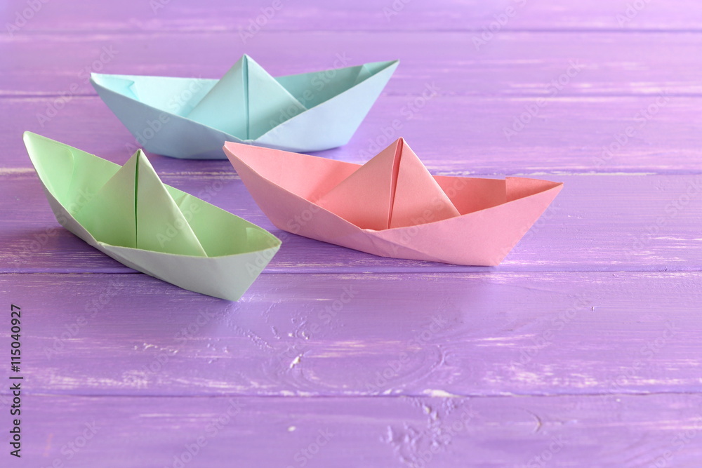 Three colorful paper ships on lilac wooden table. Easy to make origami ...