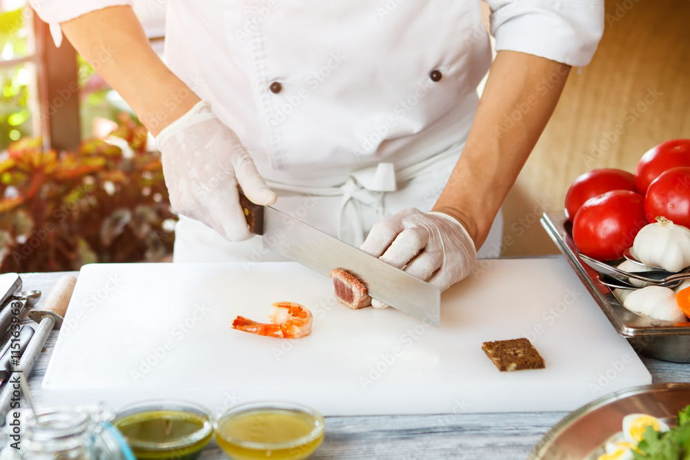 Hand with knife cuts meat. Small slice of brown bread. Juicy fried tuna ...