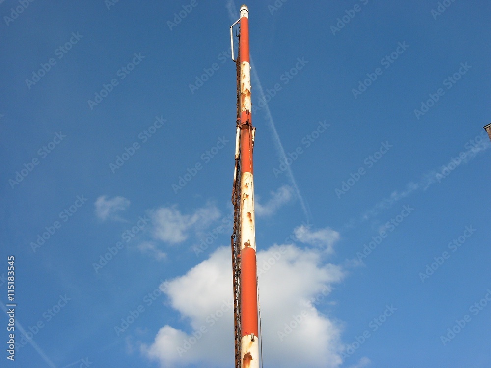 Alter rostiger rotweißer Schlagbaum vor blauem Himmel mit weißen Wolken ...