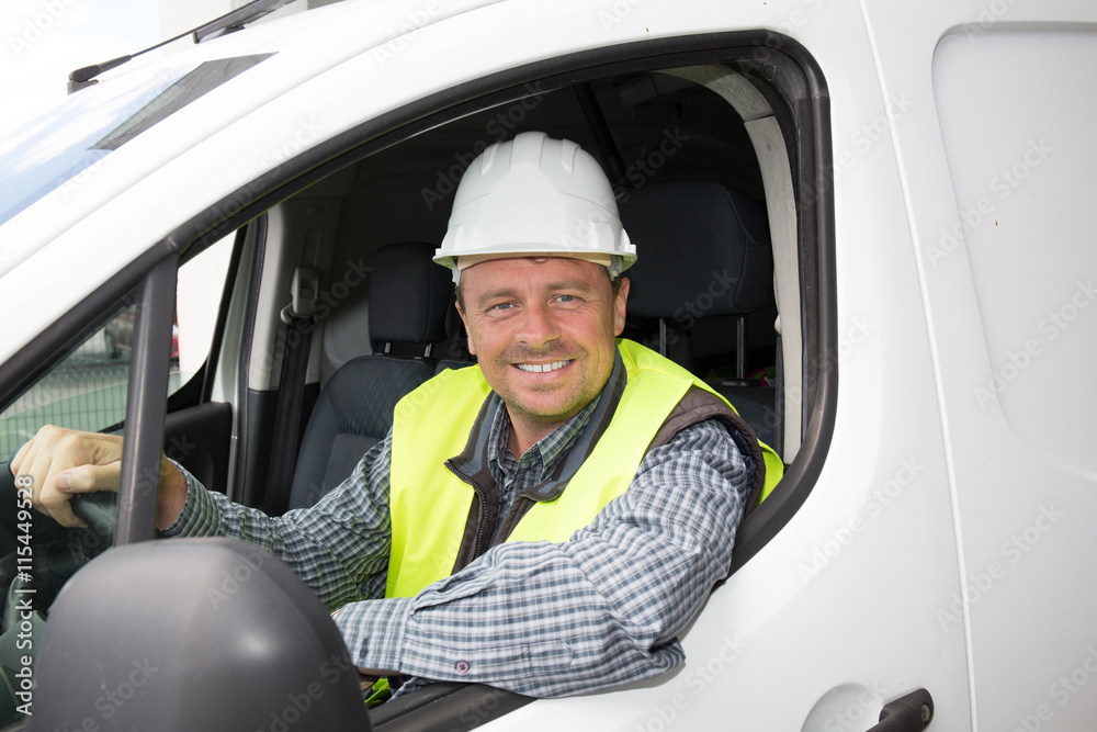 Construction worker driving a car and talking, wearing white helmet ...