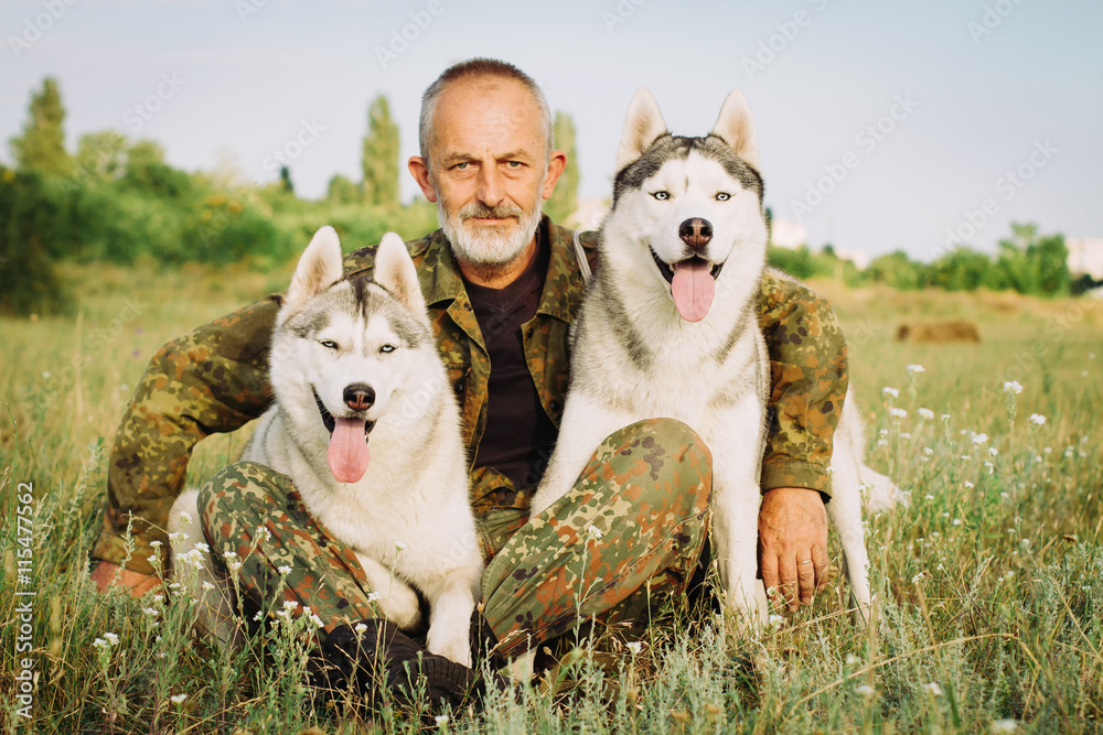 Old man with a beard sitting on a haystack with their dogs, enjoying ...