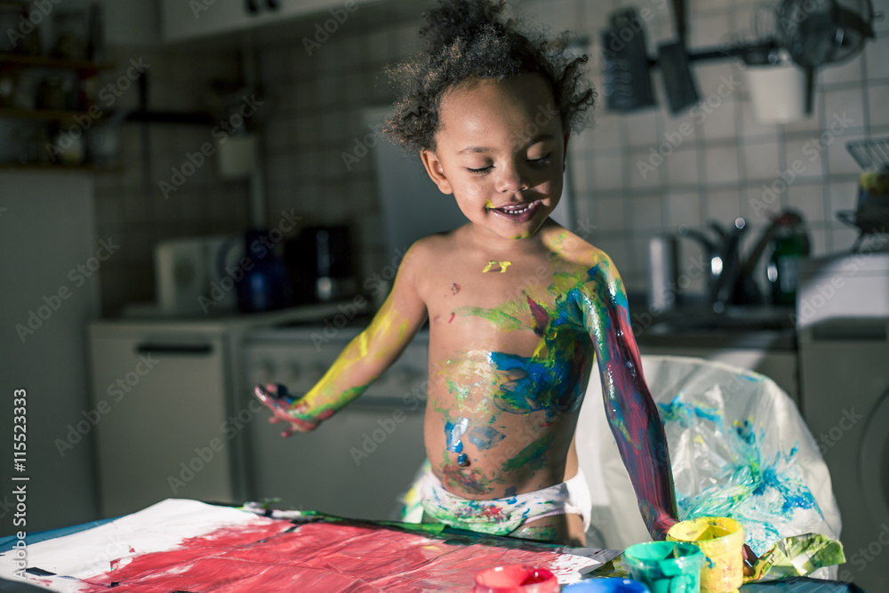 Girl draws red picture with fingerpaint and is fully smeared of colors ...