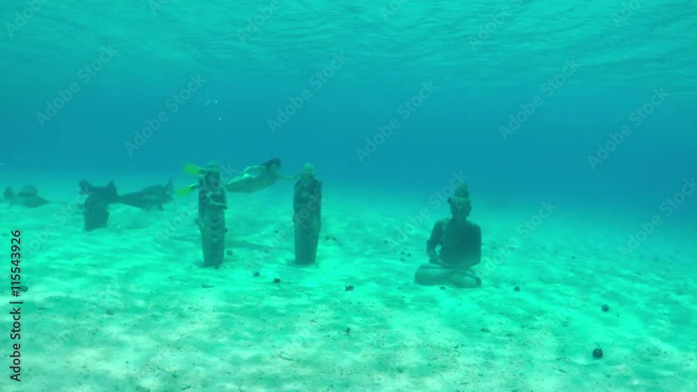 Woman diving underwater exploring sunken statues on the sea bottom ...