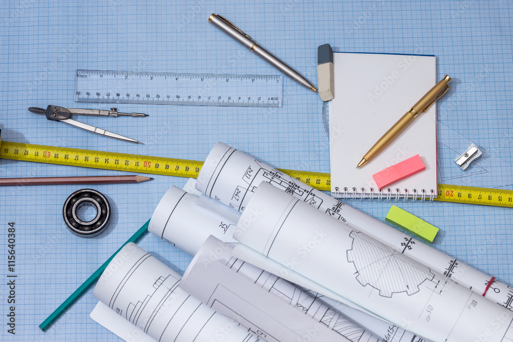 blank notepad, rolls of engineering drawings with tools on graph ...