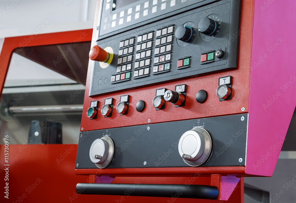 CNC machine control panel with emergency stop button on foreground ...