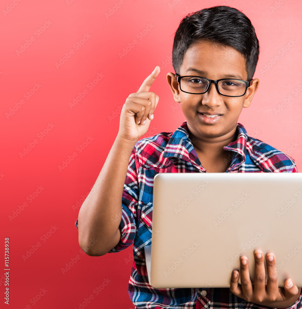 10 year old indian kid holding white laptop in hand, posing over red ...