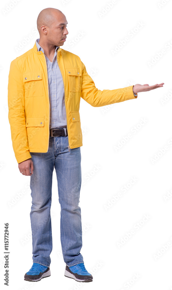 Calm young man pointing to the left with his left hand. He is holding a ...