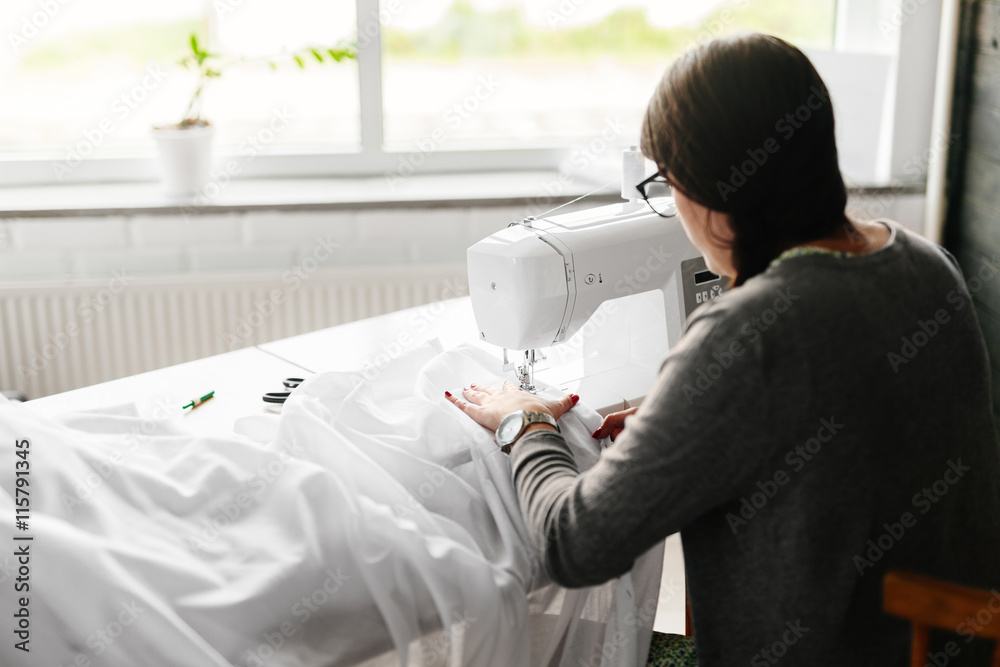 Rear view of fashion designer using sewing machine at workbench Stock ...
