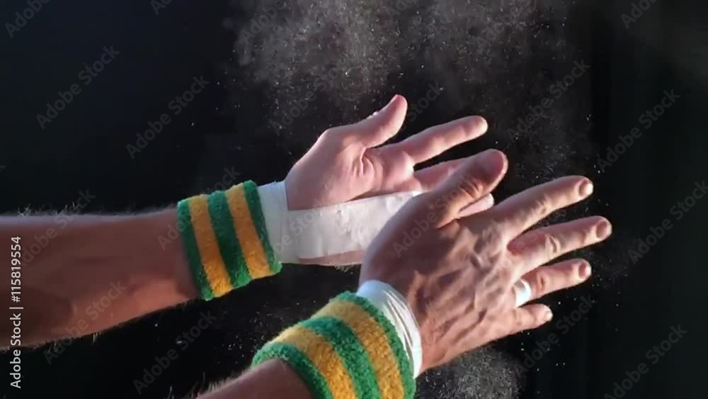 Taped hands of gymnast clapping white chalk powder into a slow motion ...