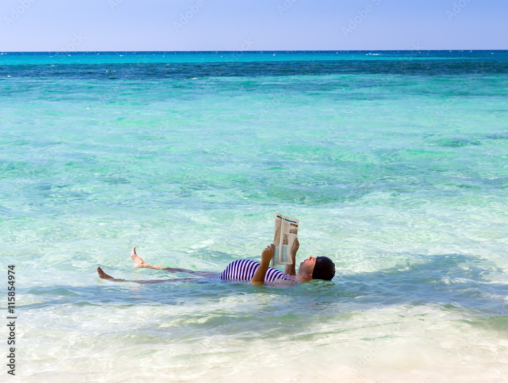 fat man in swimsuit lying in the sea and reads newspaper Stock Photo ...