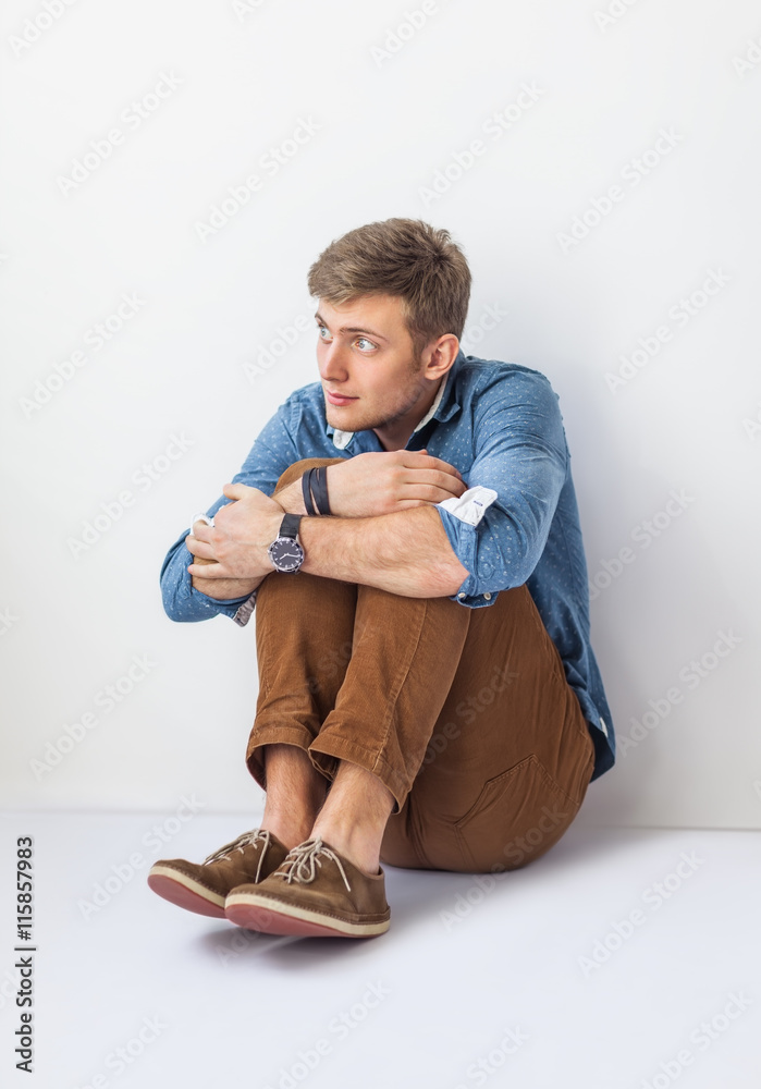 Funny scared man sitting on the floor in studio Stock Photo | Adobe Stock