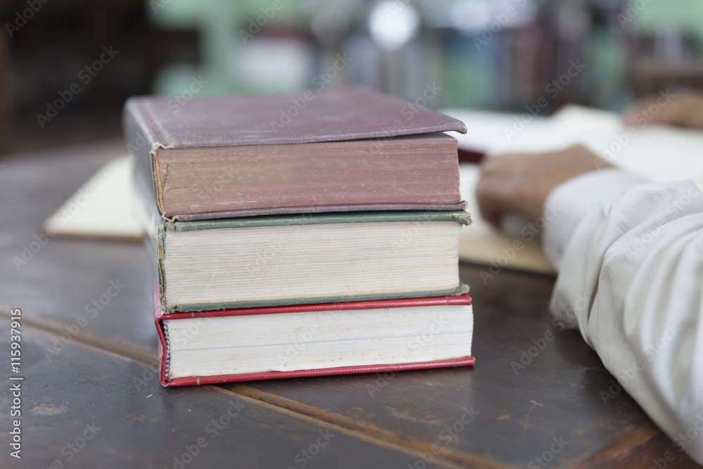 man reading book with textbook stack on wooden desk Stock-Foto | Adobe ...