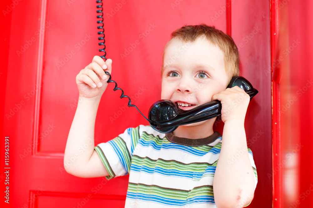 child holding a telephone receiver and smiling. cute boy talking on the ...
